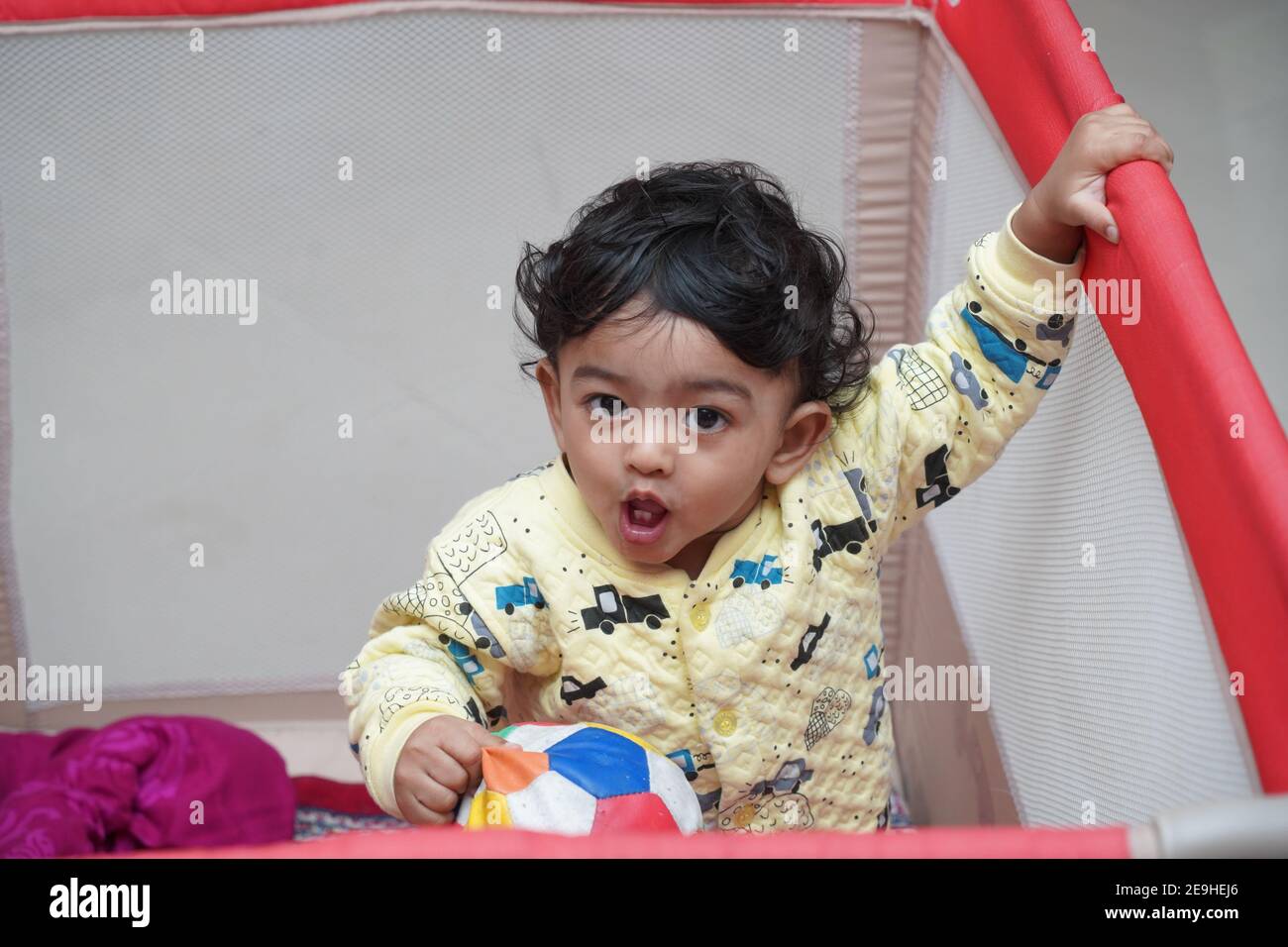 Little Asian baby with a cute look playing with a ball in the cradle ...