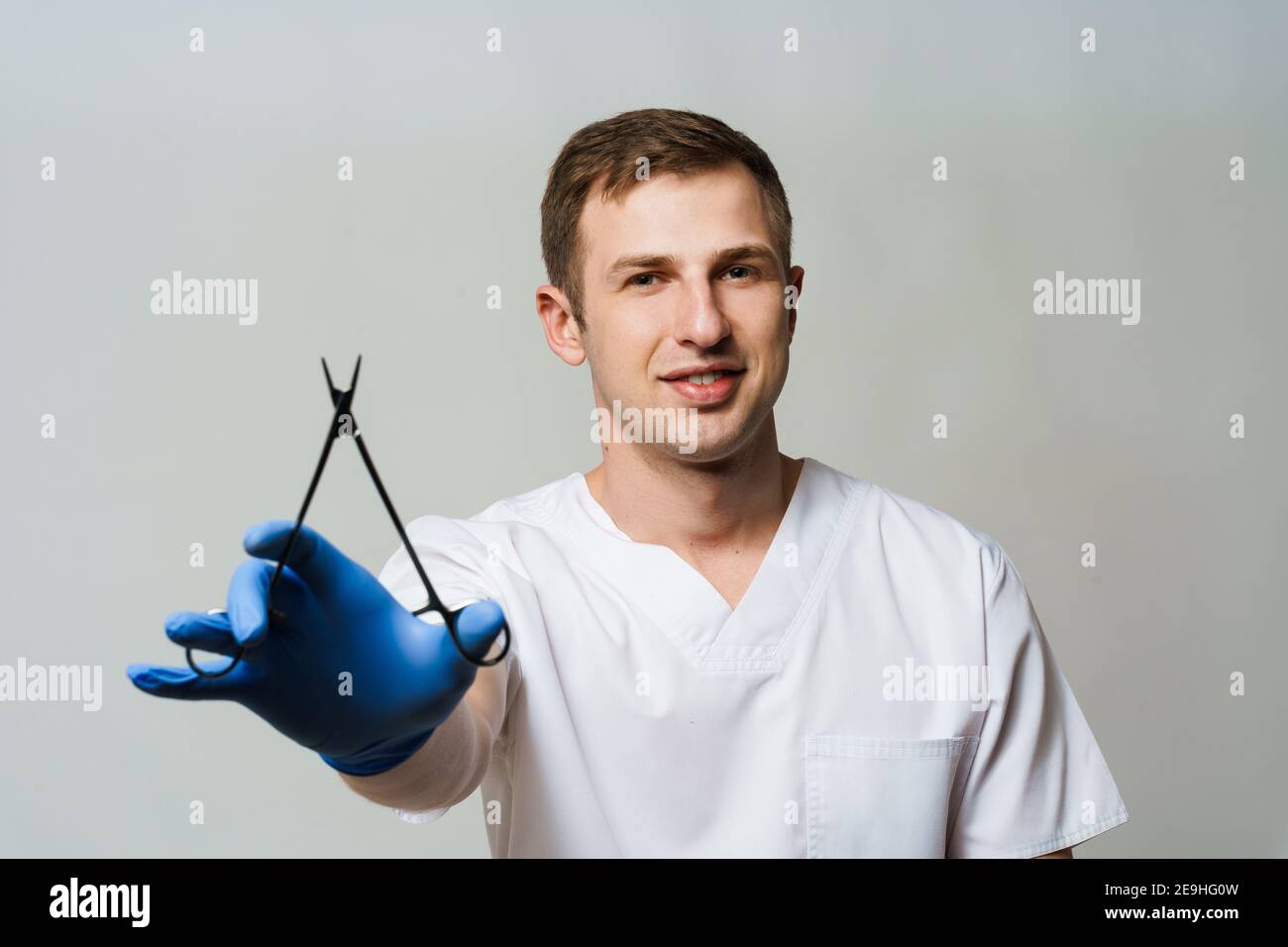 Doctor surgeon with needle holder in medical gloves on white background ...