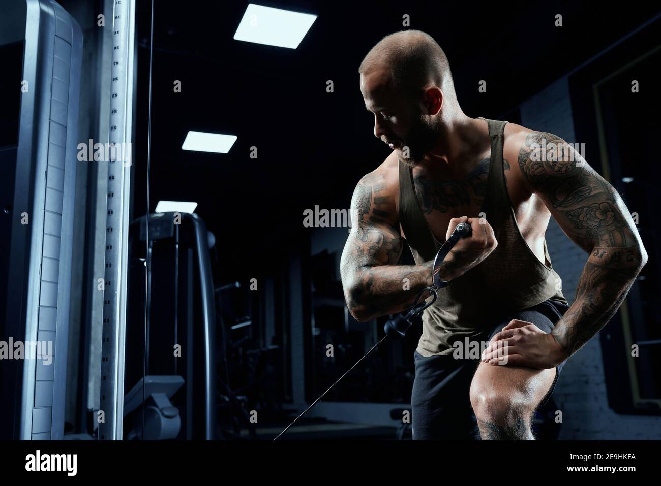 Portrait of muscular tattooed bodybuilder doing crossover exercise ...