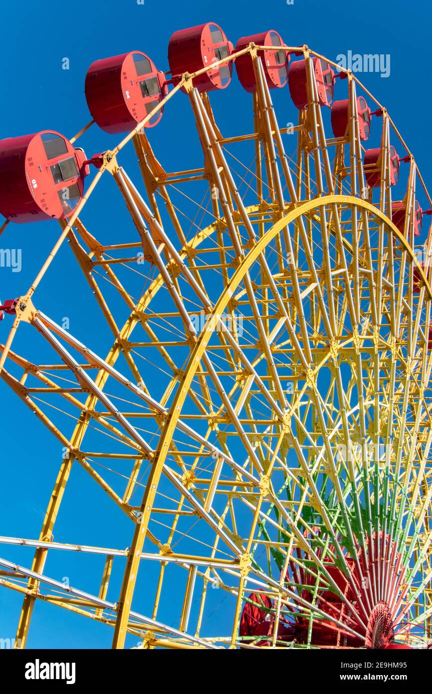 Ferris wheel with red cabins rotate against blue sky Stock Photo - Alamy