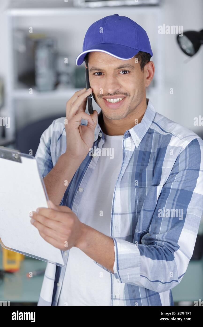 courier holding clipboard and making a phone call Stock Photo - Alamy