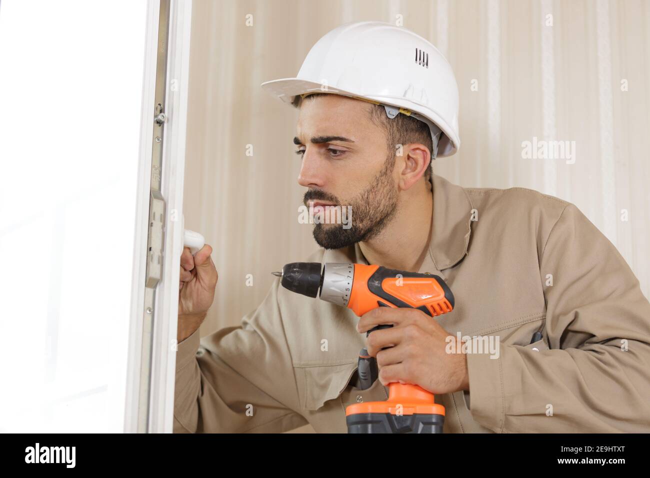 male builder working on window frame Stock Photo - Alamy