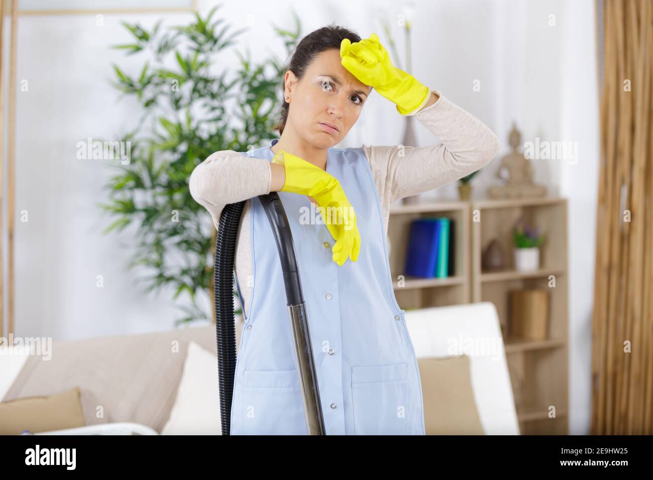 unhappy cleaner tired from hoovering Stock Photo - Alamy