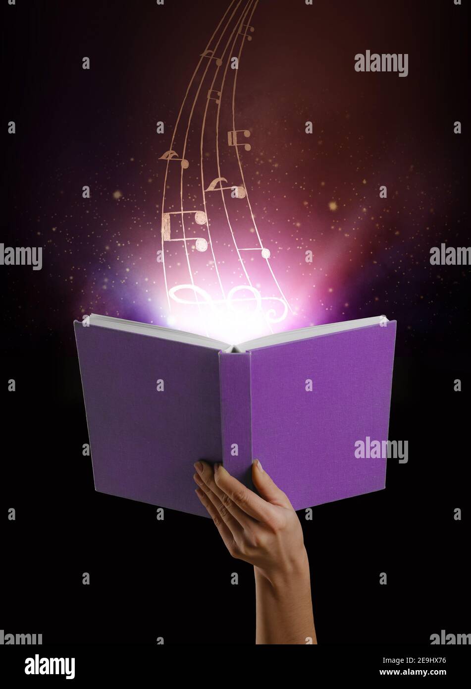 Female hand holding open book with flying music notes on dark ...