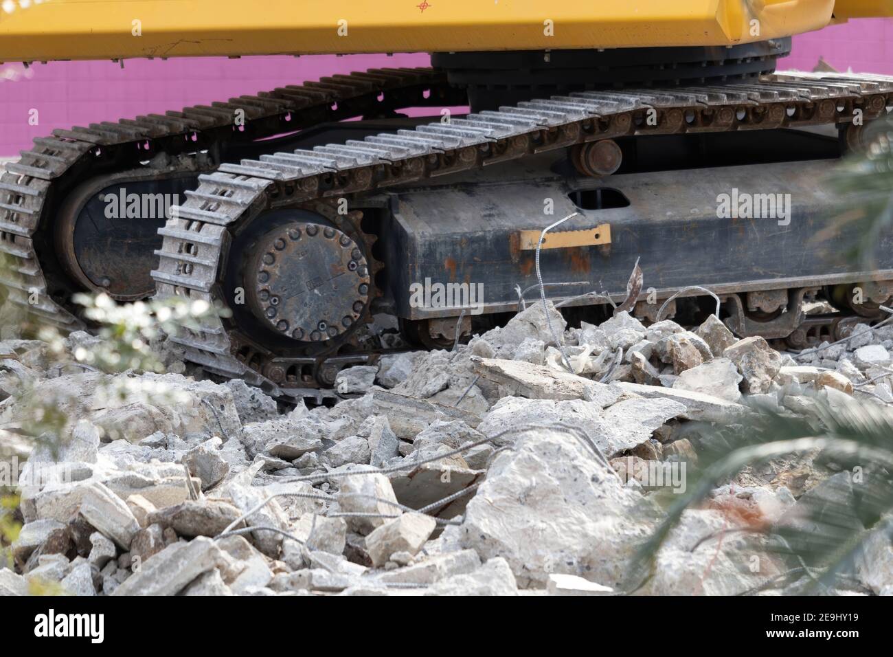 Tracks of a demolition rig, claw their way through the rubble of a ...