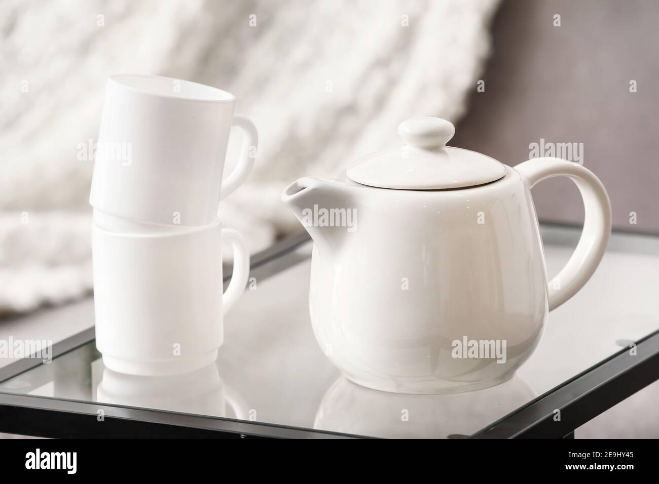 Stylish teapot and cups on table in room Stock Photo - Alamy