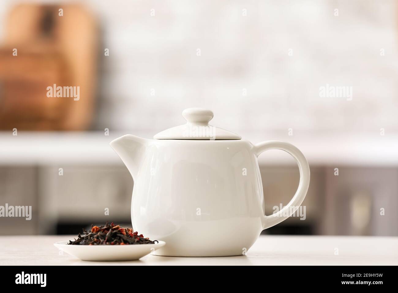 Teapot and dry tea leaves on light table in room Stock Photo - Alamy