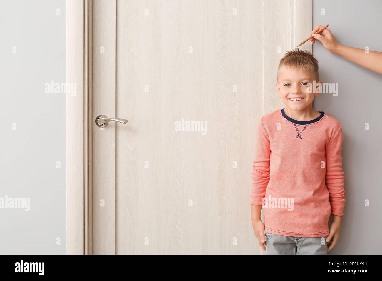 Female hand with pencil and cute little boy measuring height near ...