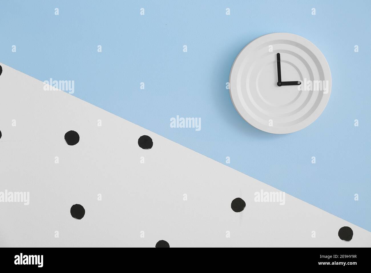 Stylish clock hanging on color wall Stock Photo - Alamy