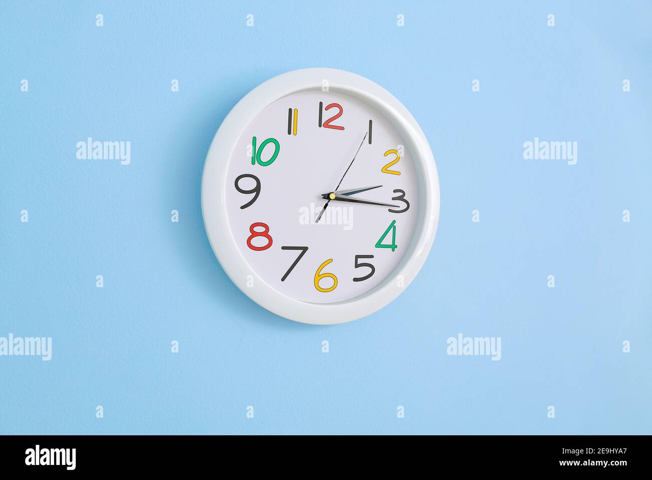 Stylish clock hanging on color wall Stock Photo - Alamy