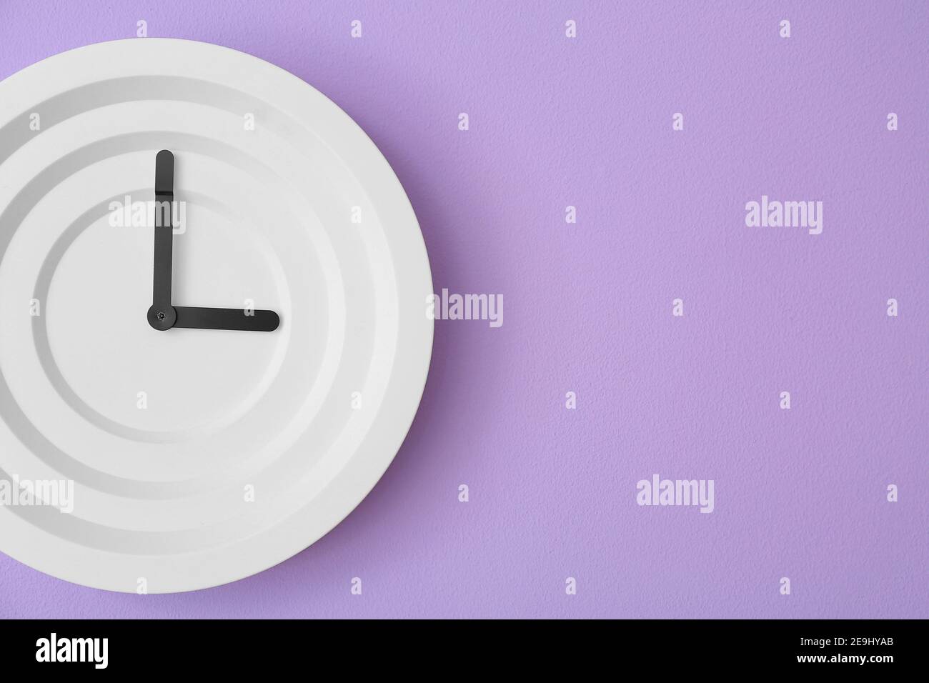 Stylish clock hanging on color wall Stock Photo - Alamy