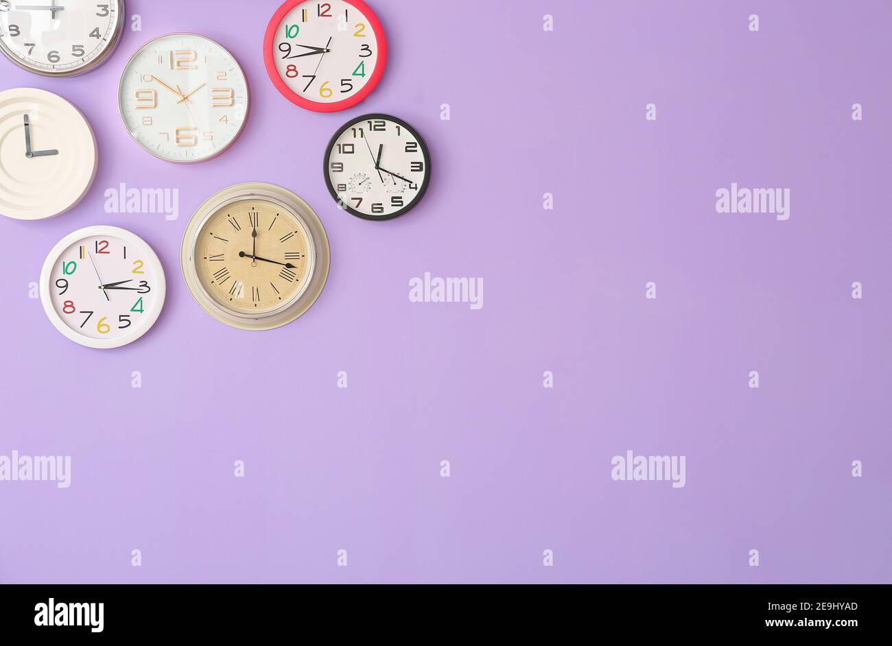 Different clocks hanging on color wall Stock Photo - Alamy