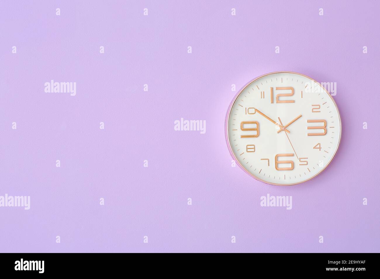 Stylish clock hanging on color wall Stock Photo - Alamy
