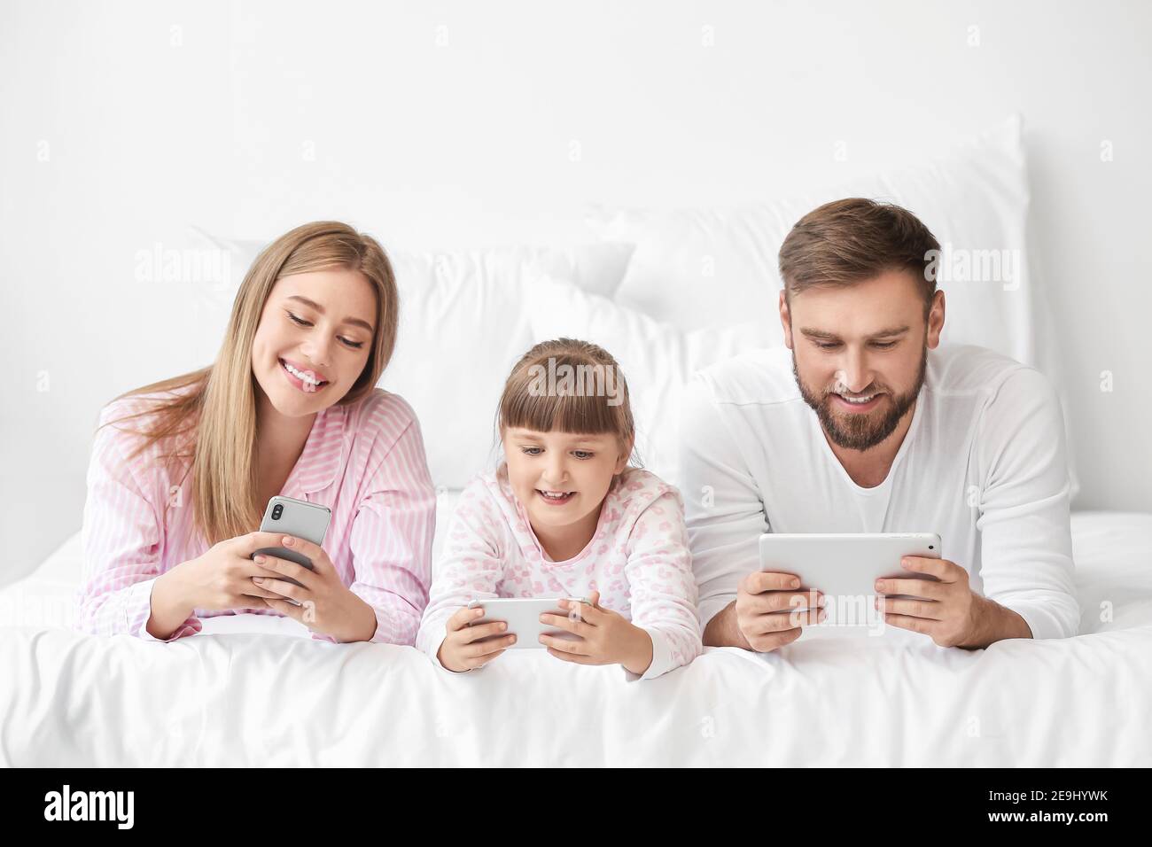 Happy family with mobile phones in bedroom Stock Photo - Alamy
