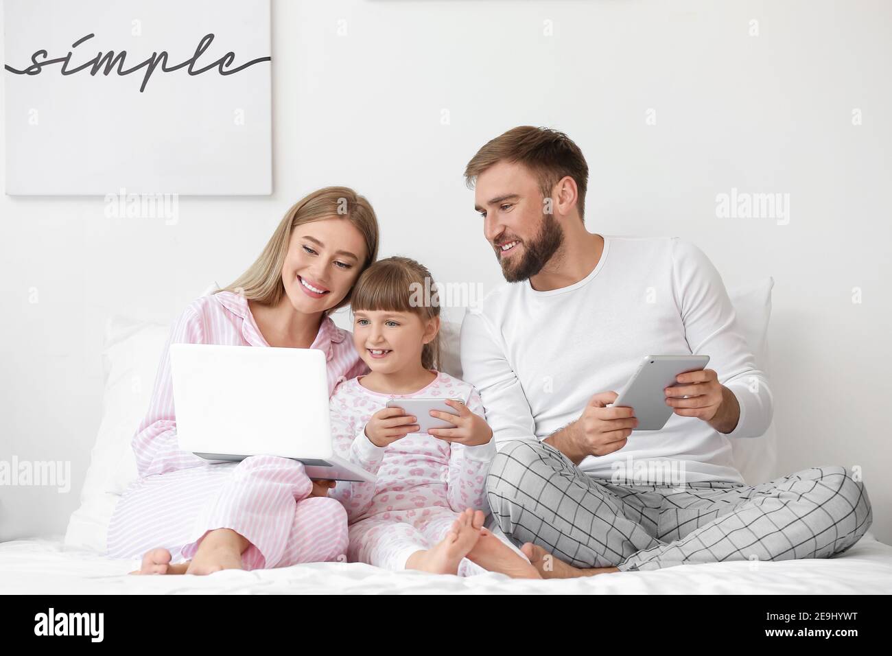 Happy family with modern devices in bedroom Stock Photo - Alamy