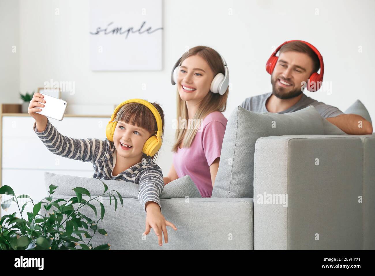 Happy family with mobile phone and headphones at home Stock Photo - Alamy