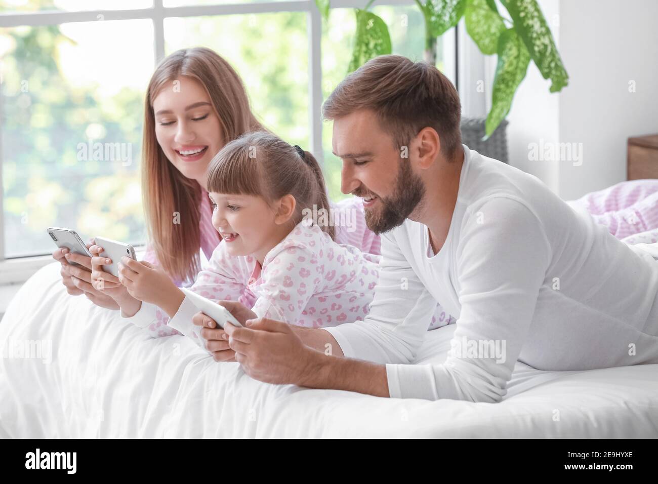 Happy family with mobile phones in bedroom Stock Photo - Alamy