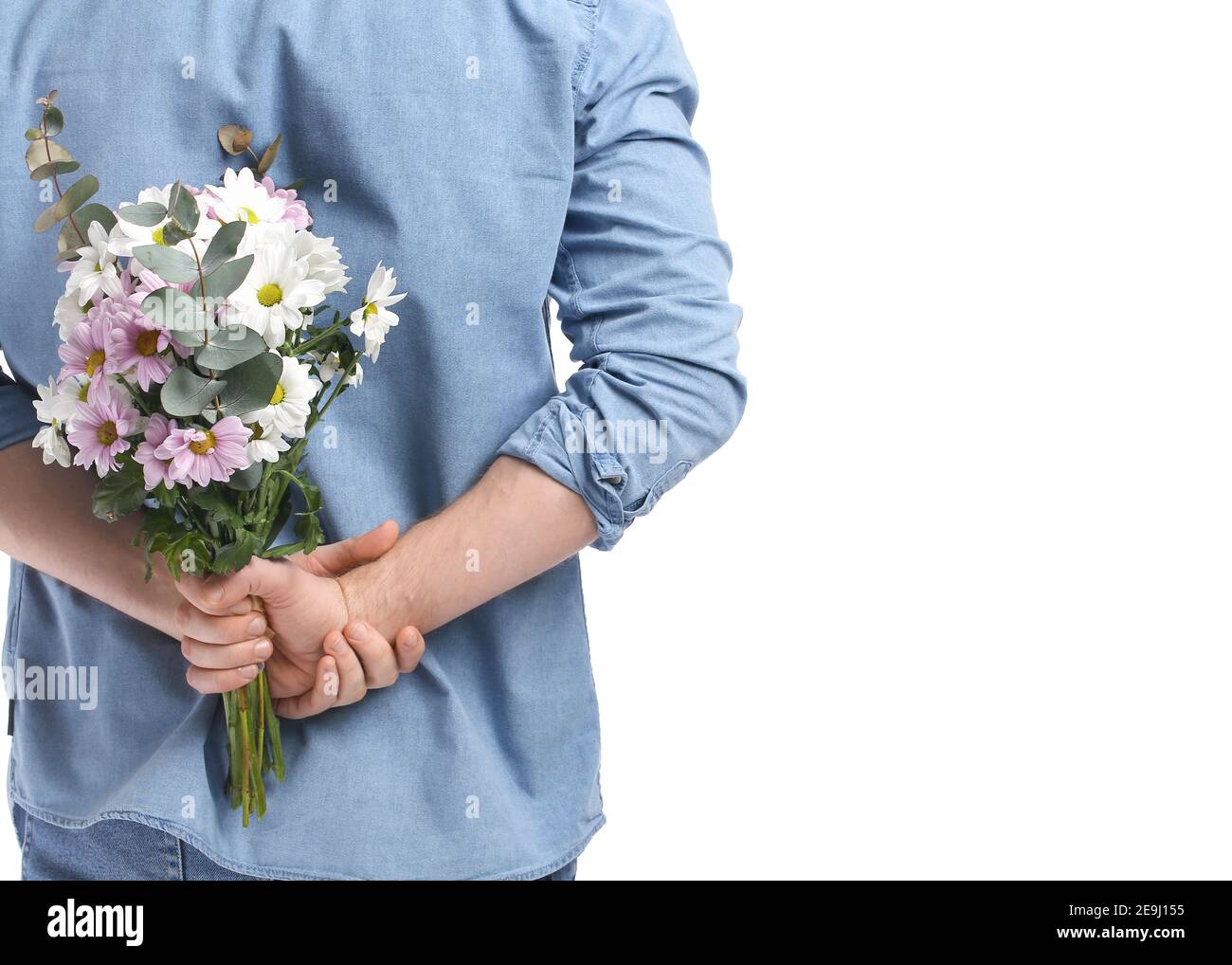 Handsome man hiding bouquet of beautiful flowers behind back on white ...