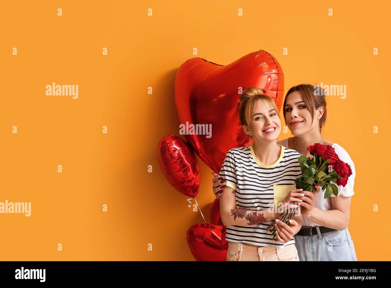 Young transgender couple with flowers and air balloons on color ...