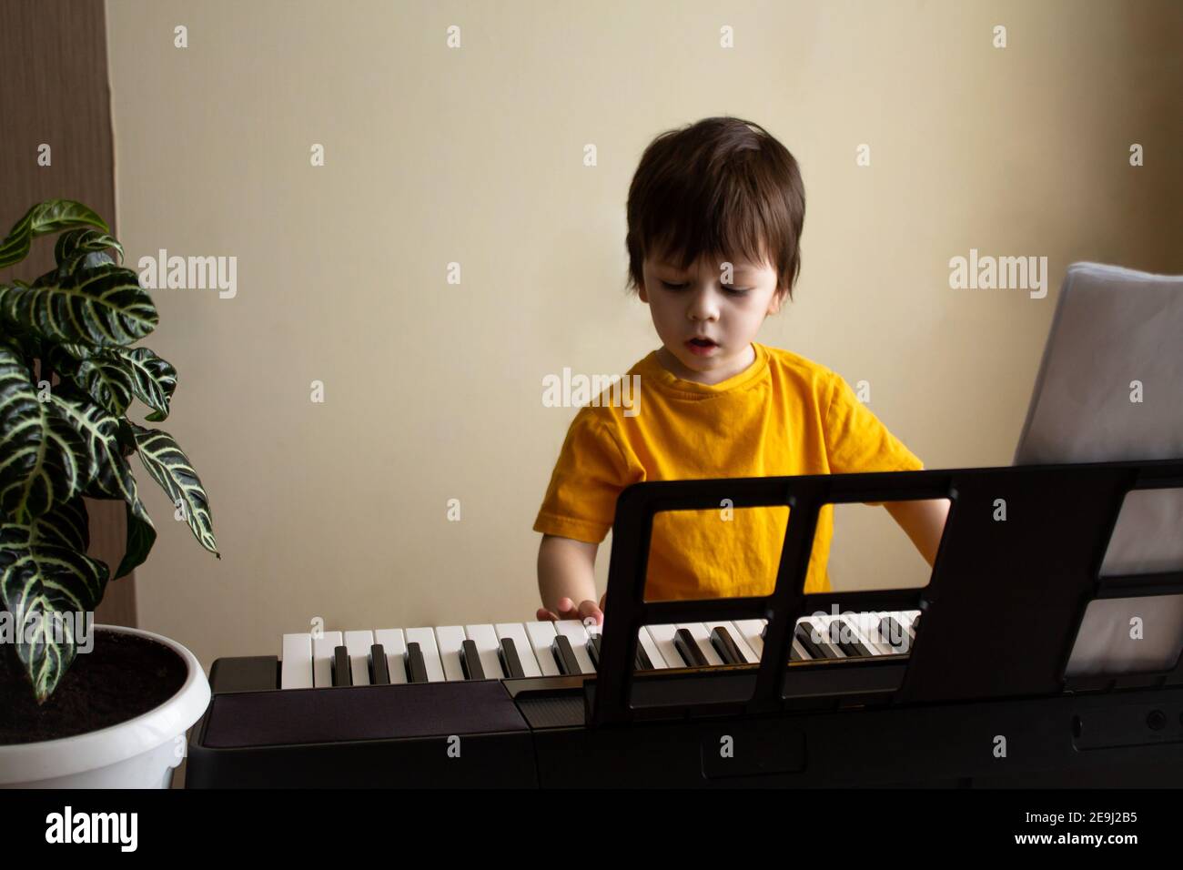 A boy playing the synthesizer. Toddler learning how to play piano ...