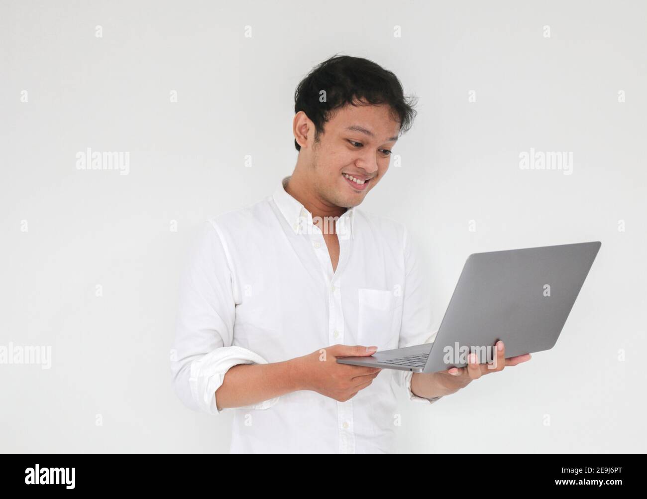 Young asian man is smile and enjoy when working at home with laptop ...