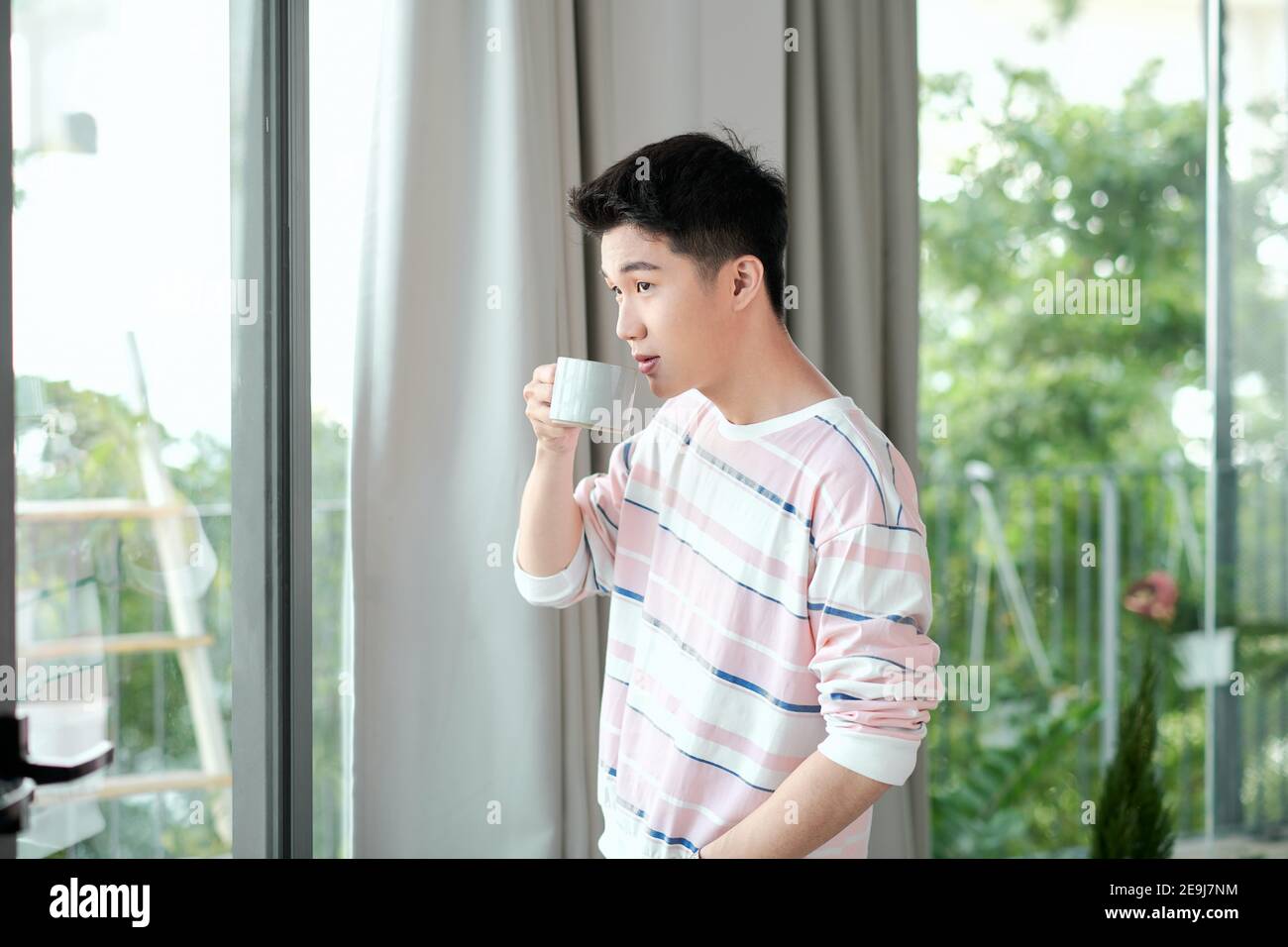 Man with drink near window indoors. Lazy morning Stock Photo - Alamy