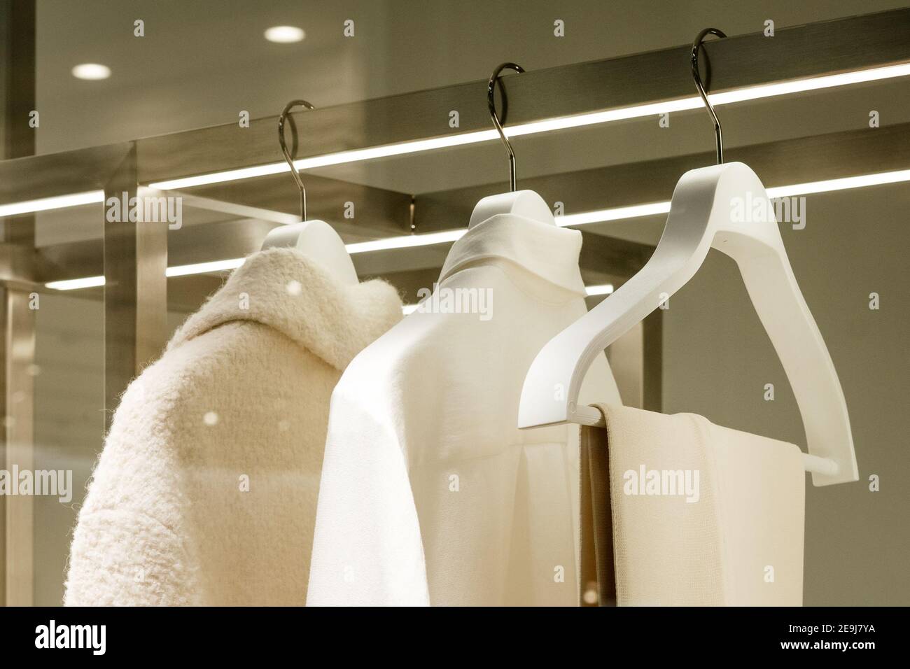 white clothes hanging on white hangers close-up Stock Photo - Alamy