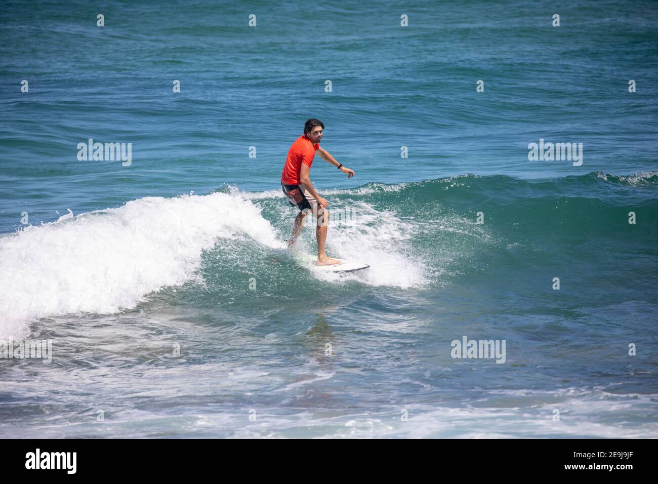 Australian man surfing off Avalon Beach I summer, warm water so no need ...