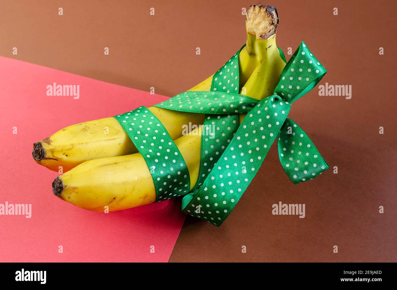Two bananas with green ribbon, stock photo. Ripe bananas on brown and ...