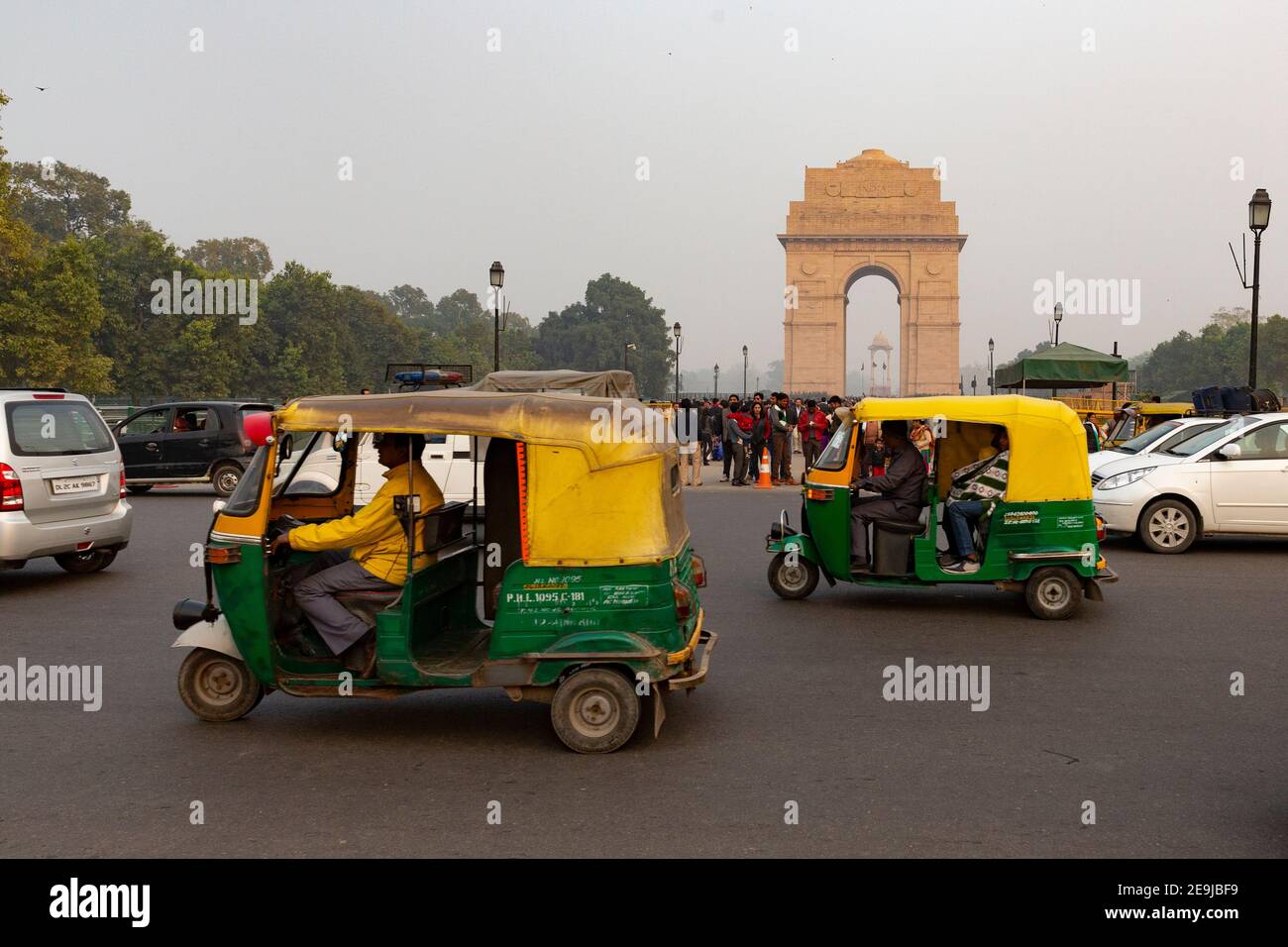 Traffic of Tuk tuks and cars pass India Gate. India Gate, designed by ...