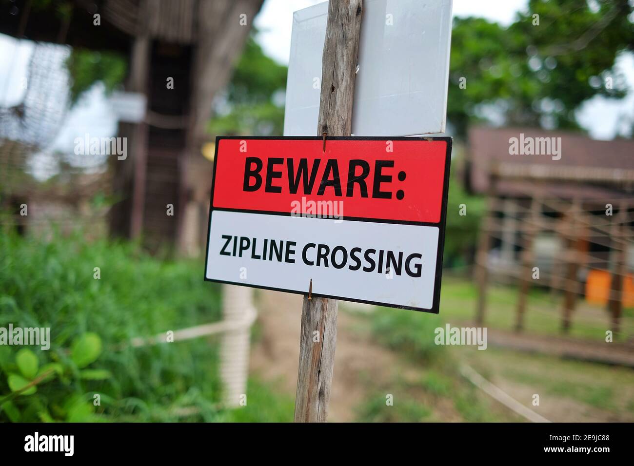 A warning along a hike trail indicating a zip line crossing up above to ...