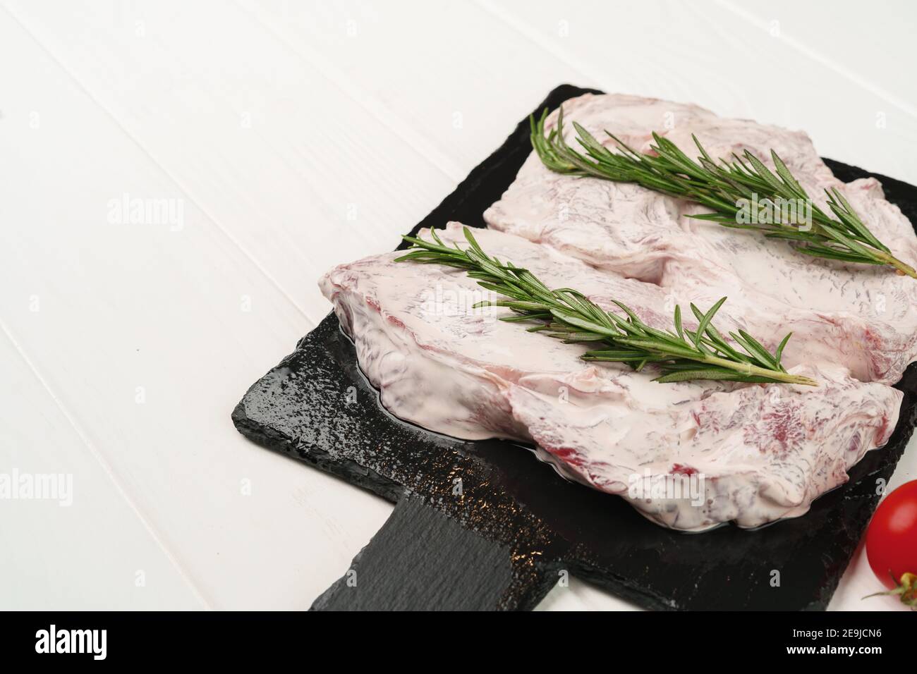 Two marinated raw beef steaks on black stone board Stock Photo - Alamy