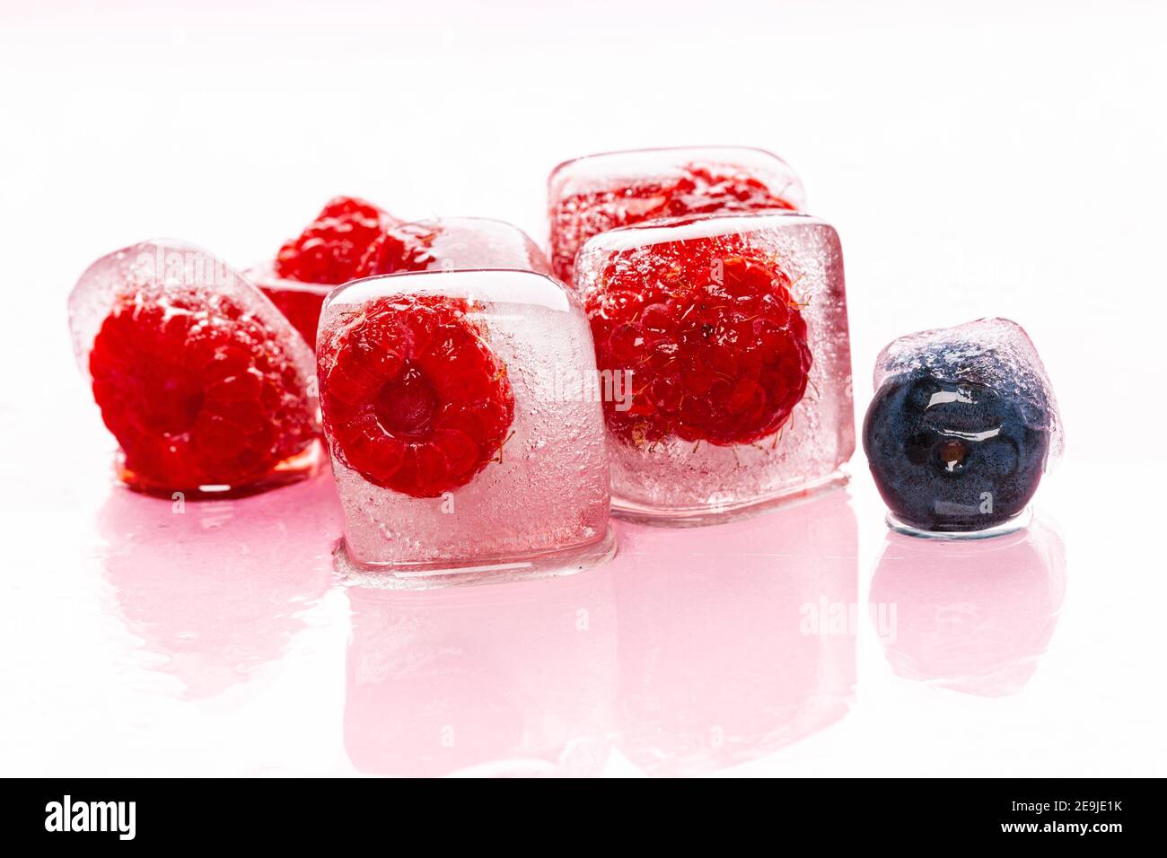 Raspberry ice cubes on pink glossy background Stock Photo - Alamy