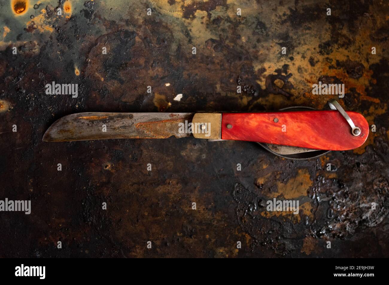 An old knife covered in rust. Knife with a red plastic handle. Top ...