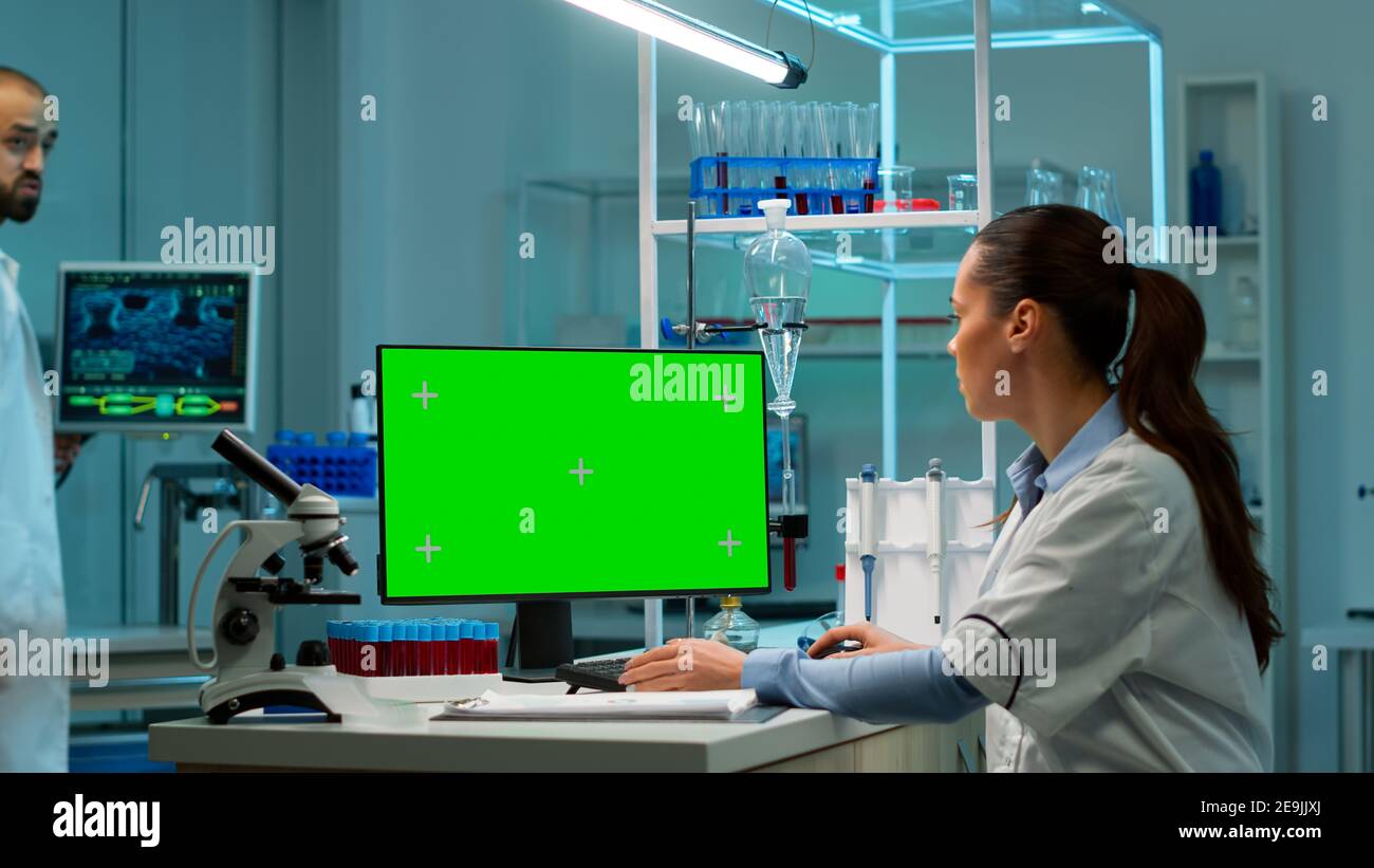 Scientist sitting at desk working on personal computer with mock-up ...