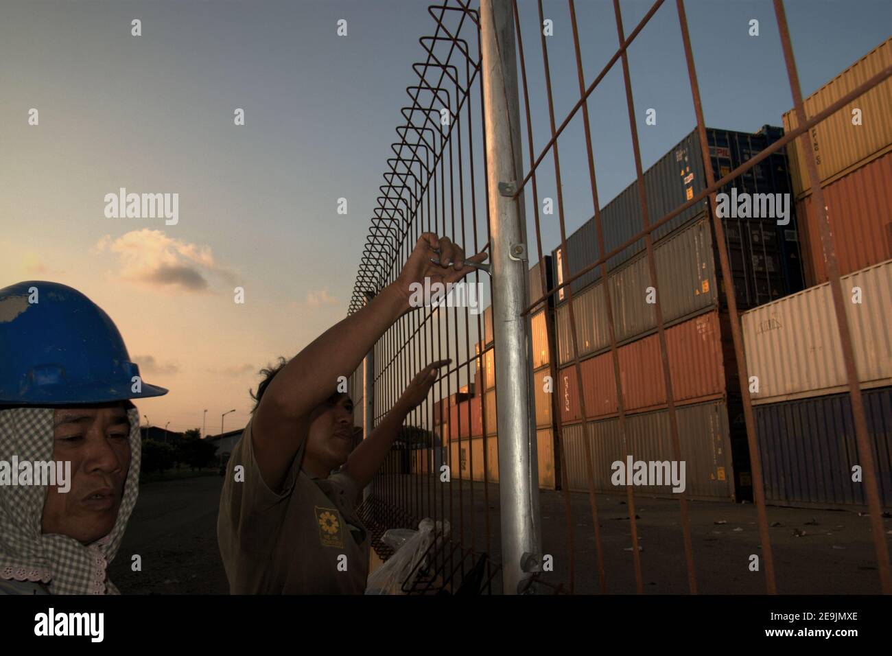 Workers running maintenance activity on the fencing of a container ...