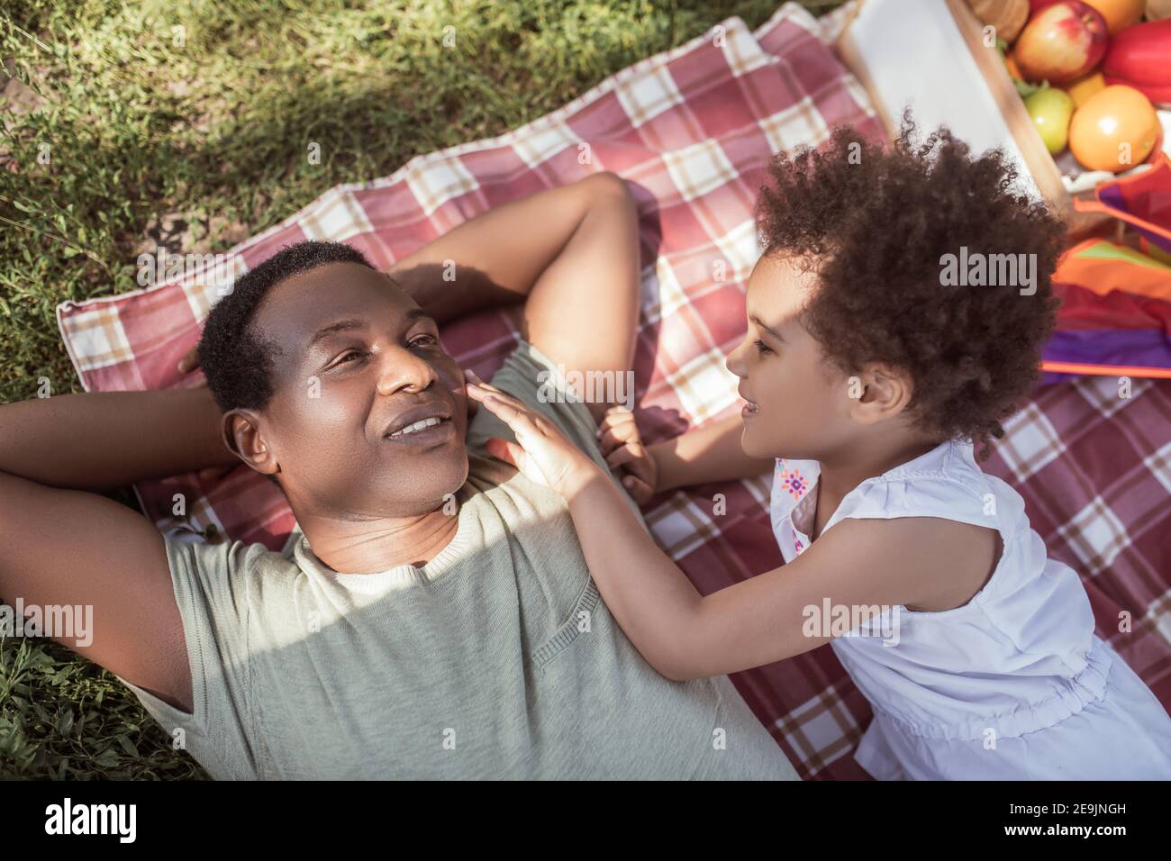African american man and his cute kid having rest in the park and ...