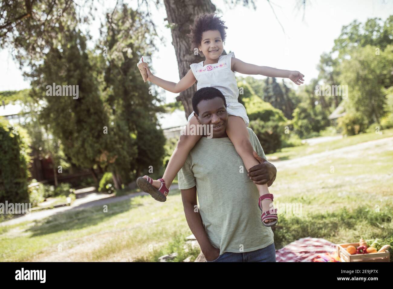 Dark-skinned cute kid sitting on her dads shoulders Stock Photo - Alamy