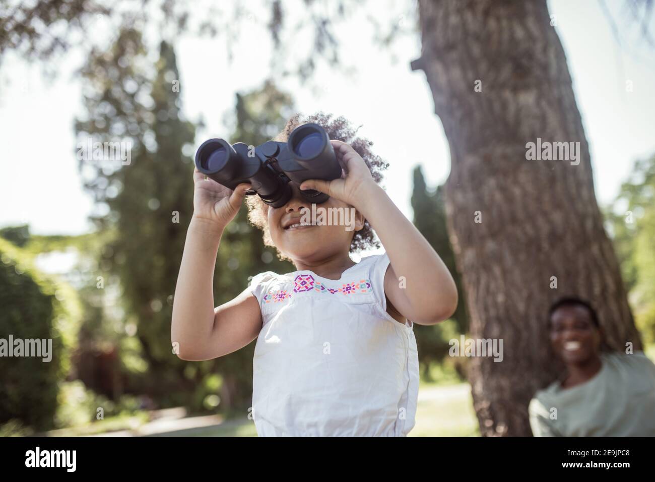 Dark-skinned cute girl holding a binocular and looking interested Stock ...