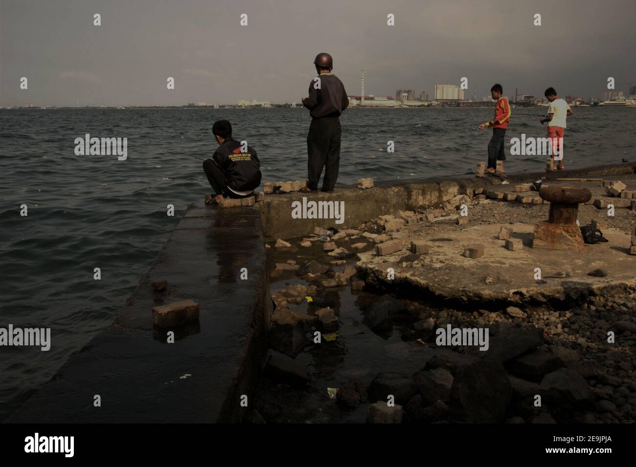 People having outdoor recreation by fishing from an abandoned harbour ...