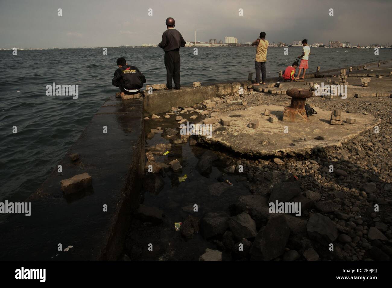 People having outdoor recreation by fishing from an abandoned harbour ...