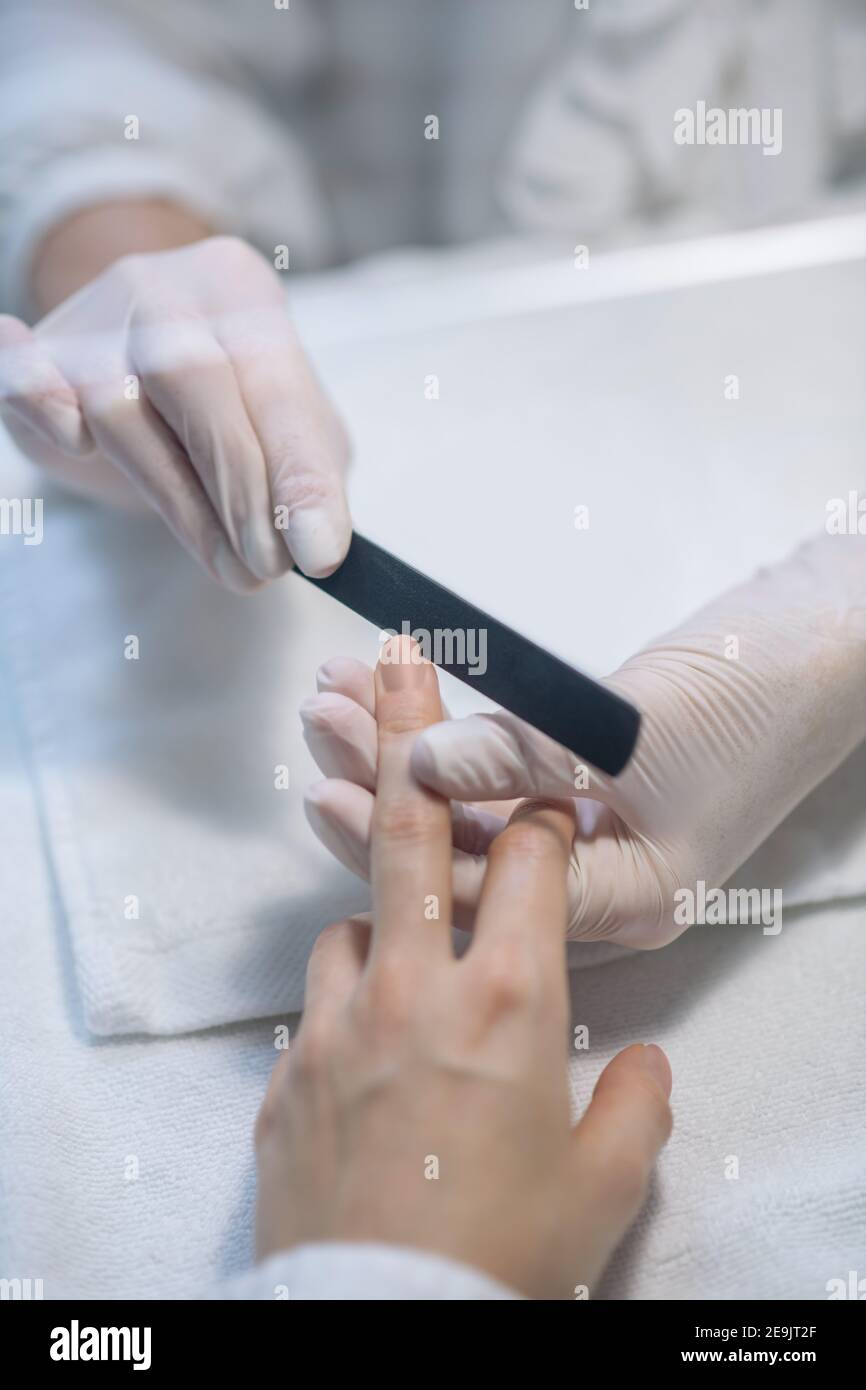 Close up picture of nail artists hands filing nails Stock Photo - Alamy