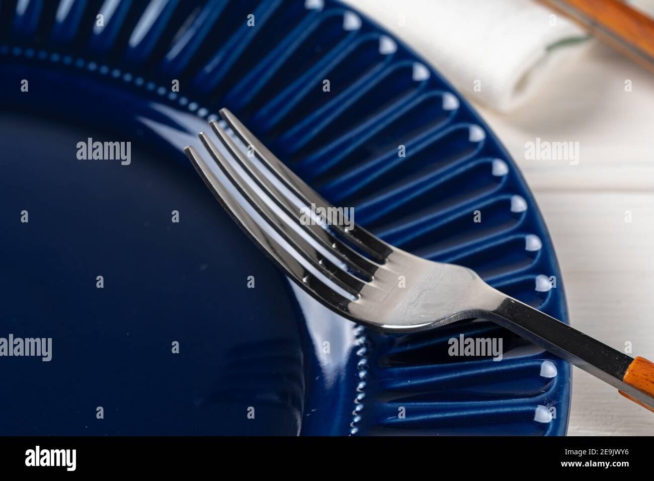 Deep blue ceramic plate with cutlery close up Stock Photo - Alamy