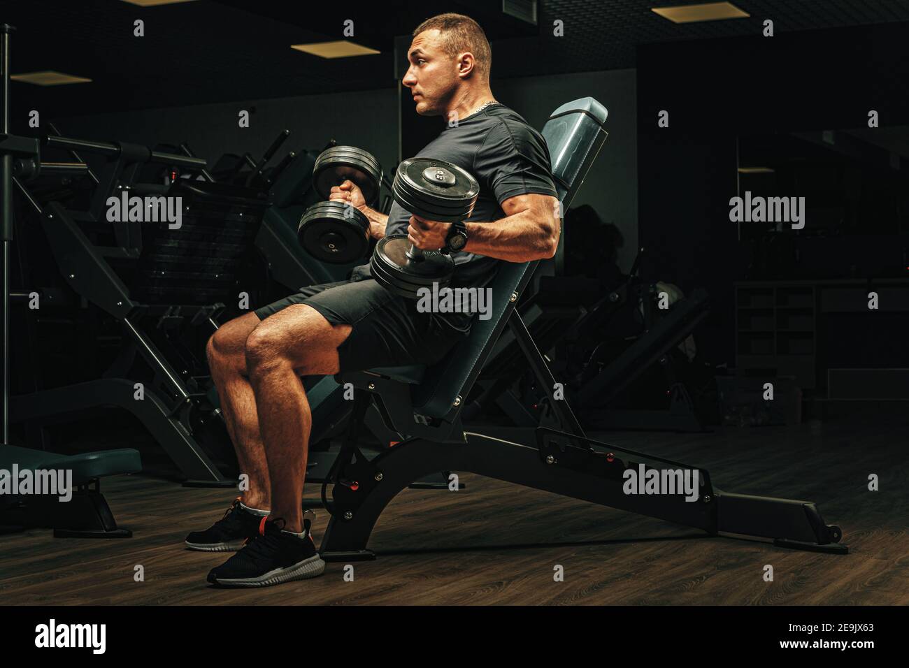 Male with sport body lifting dumbbells at the gym Stock Photo - Alamy