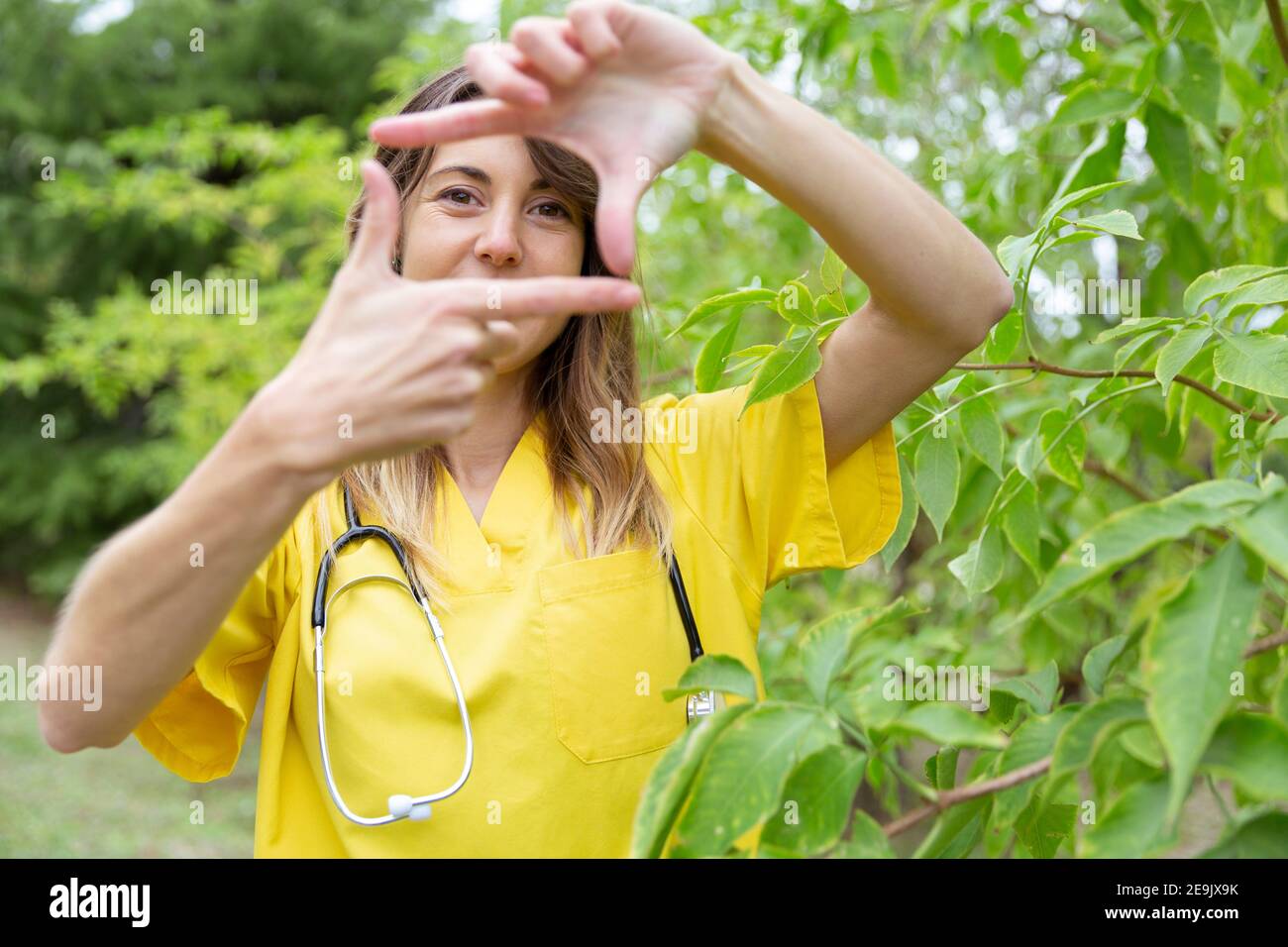 Young female nurse framing her face with her hands as a self-portrait ...