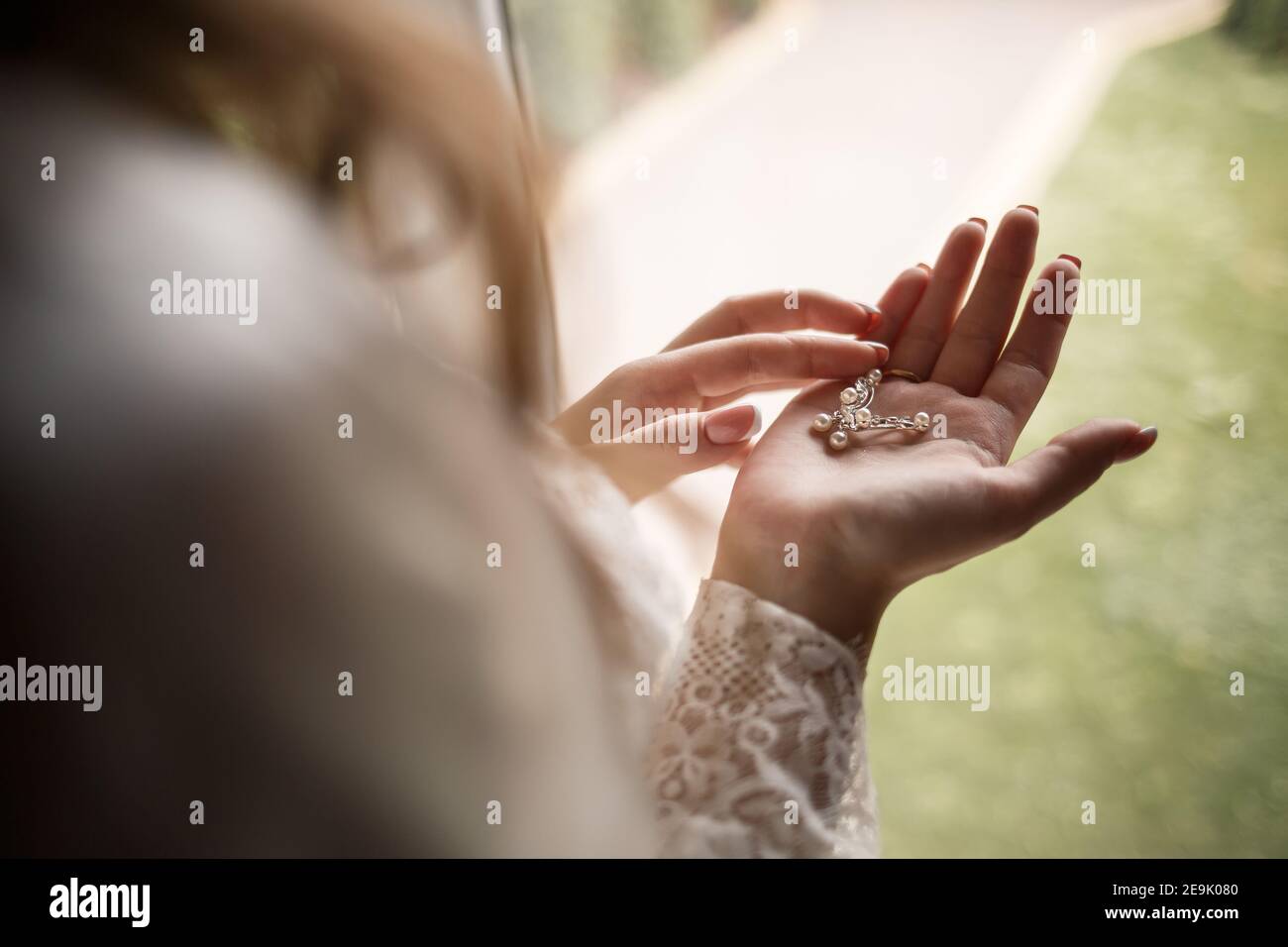 The bride holds earrings in her hand on her wedding day. Jewelry for a ...