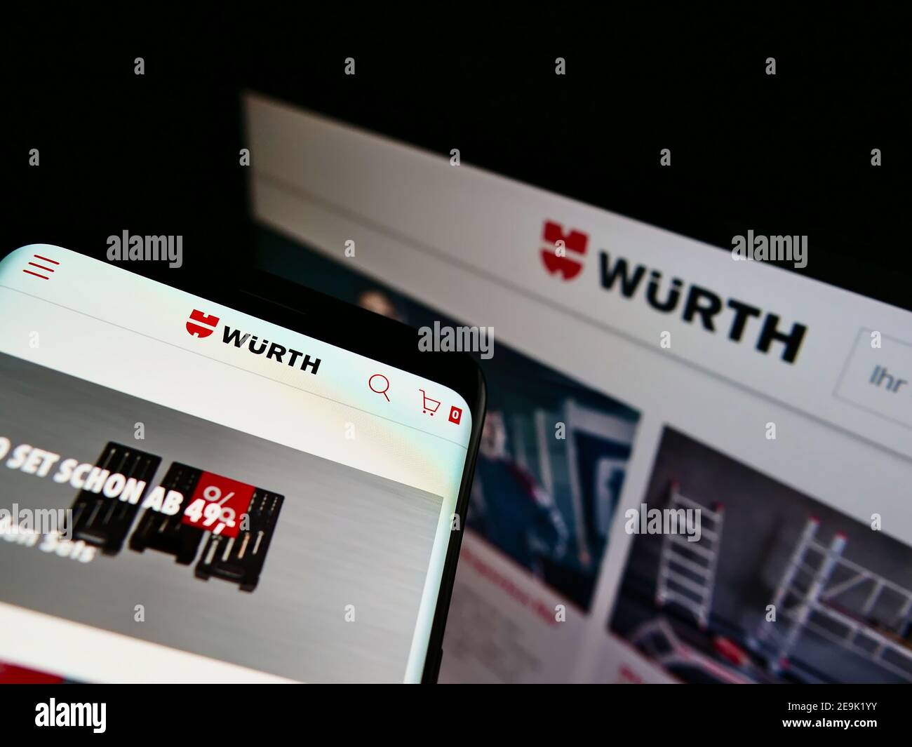 Person holding cellphone with business website and logo of German ...