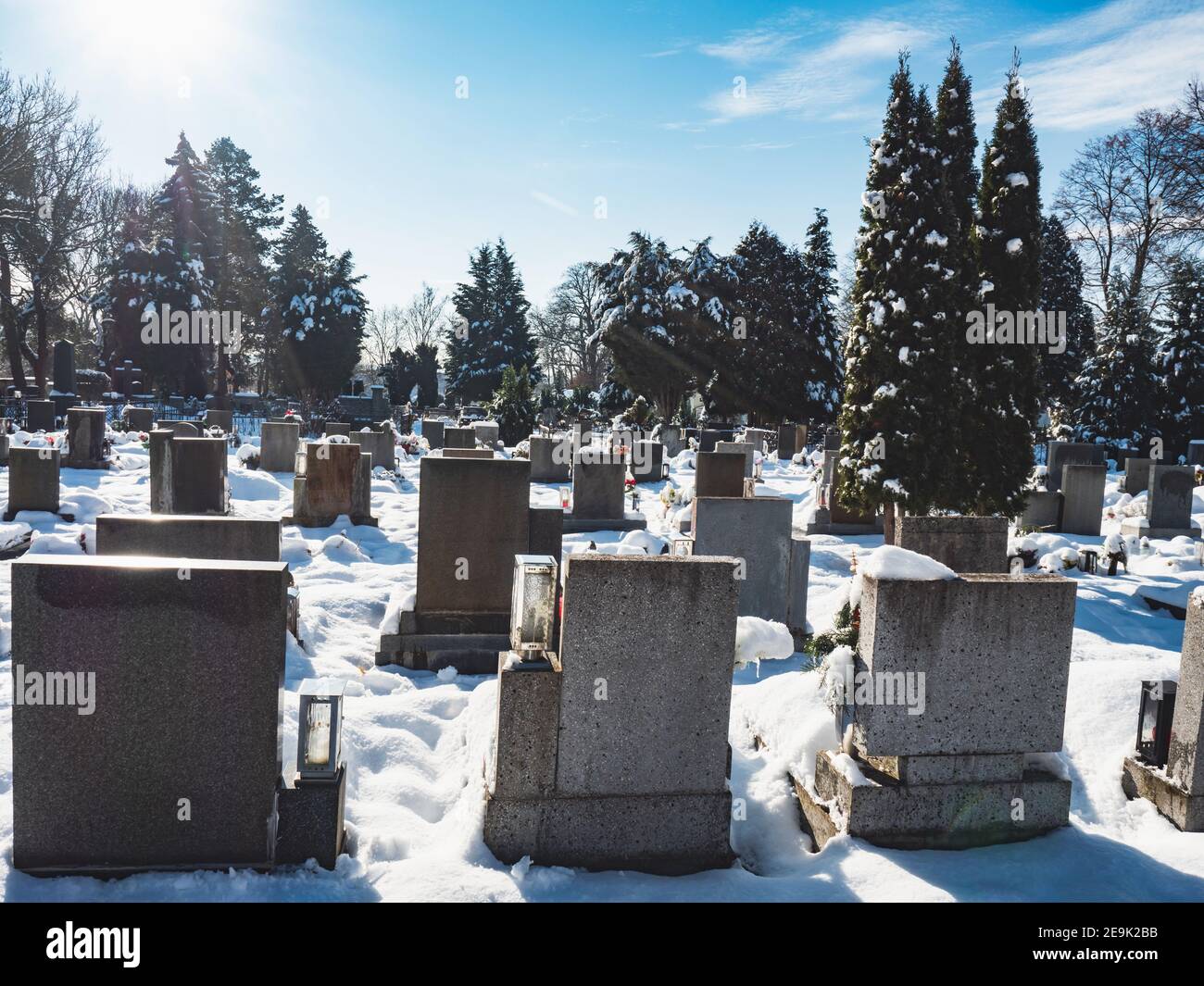 Silent snowy cemetry with headstones seen from behind in sunny winter ...