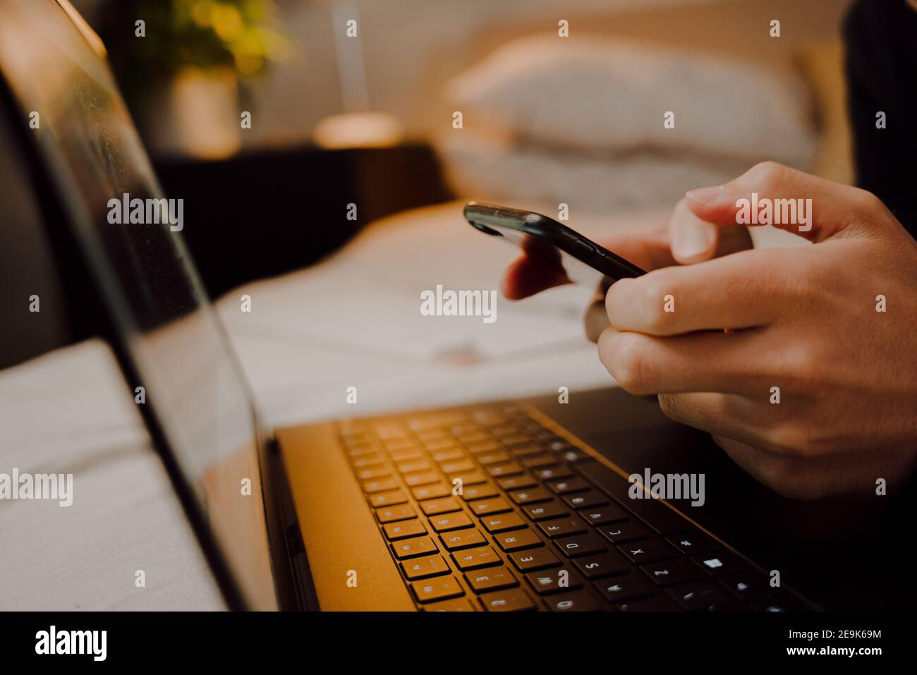 Close up male student typing on smartphone sitting at laptop taking a ...