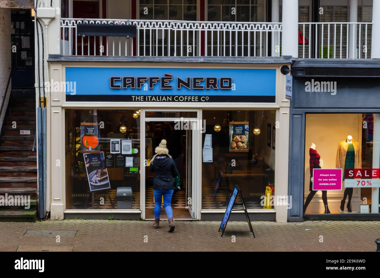 Chester; UK: Jan 29, 2021: A woman enters the Caffe Nero coffee shop on ...